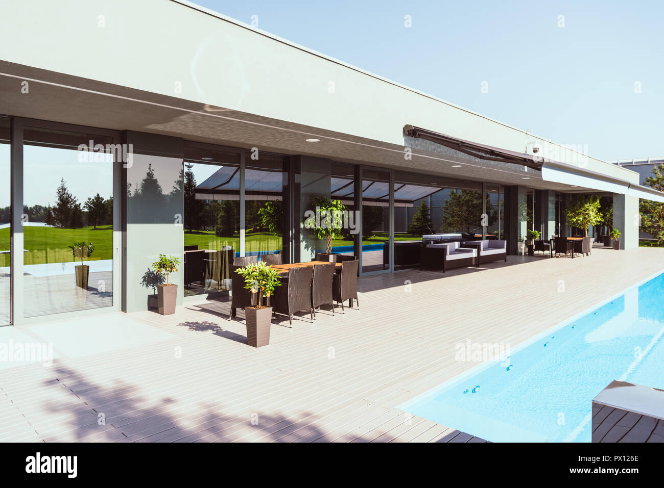 modern cottage with swimming pool, little trees, chairs and tables ...