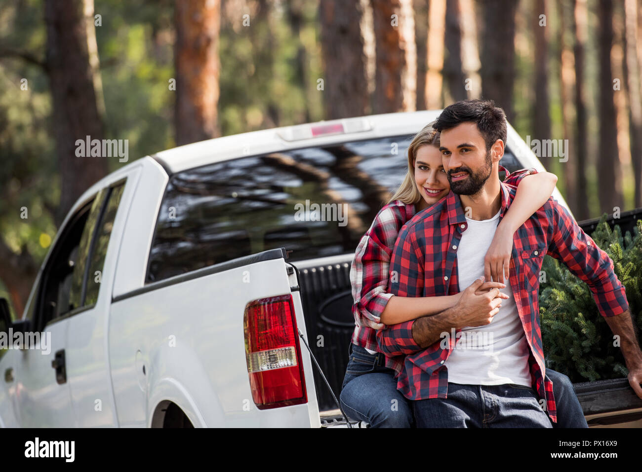 couple hugging on pickup truck with fir tree for christmas in forest ...