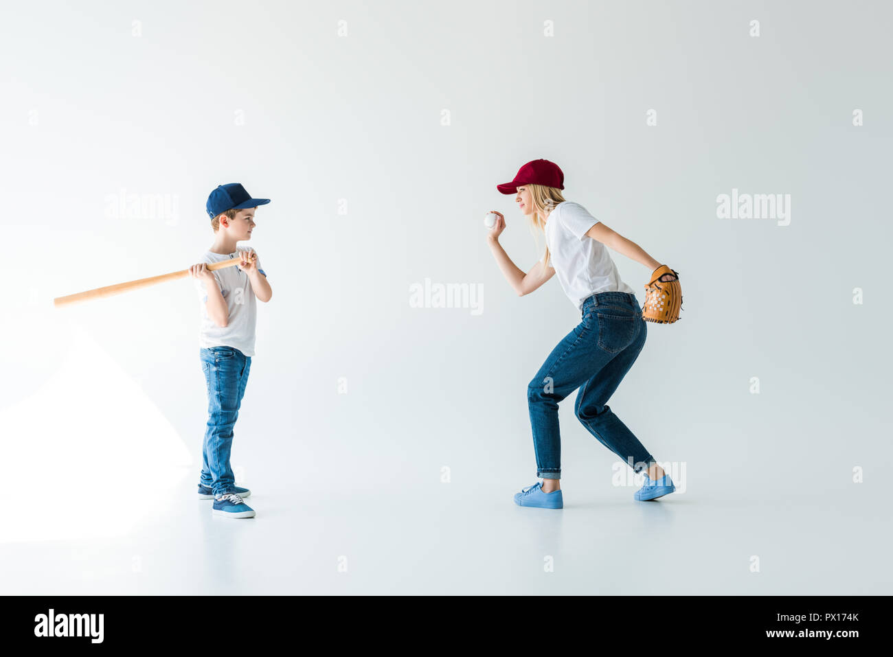 side view of mommy pitching baseball ball to son with bat isolated on ...