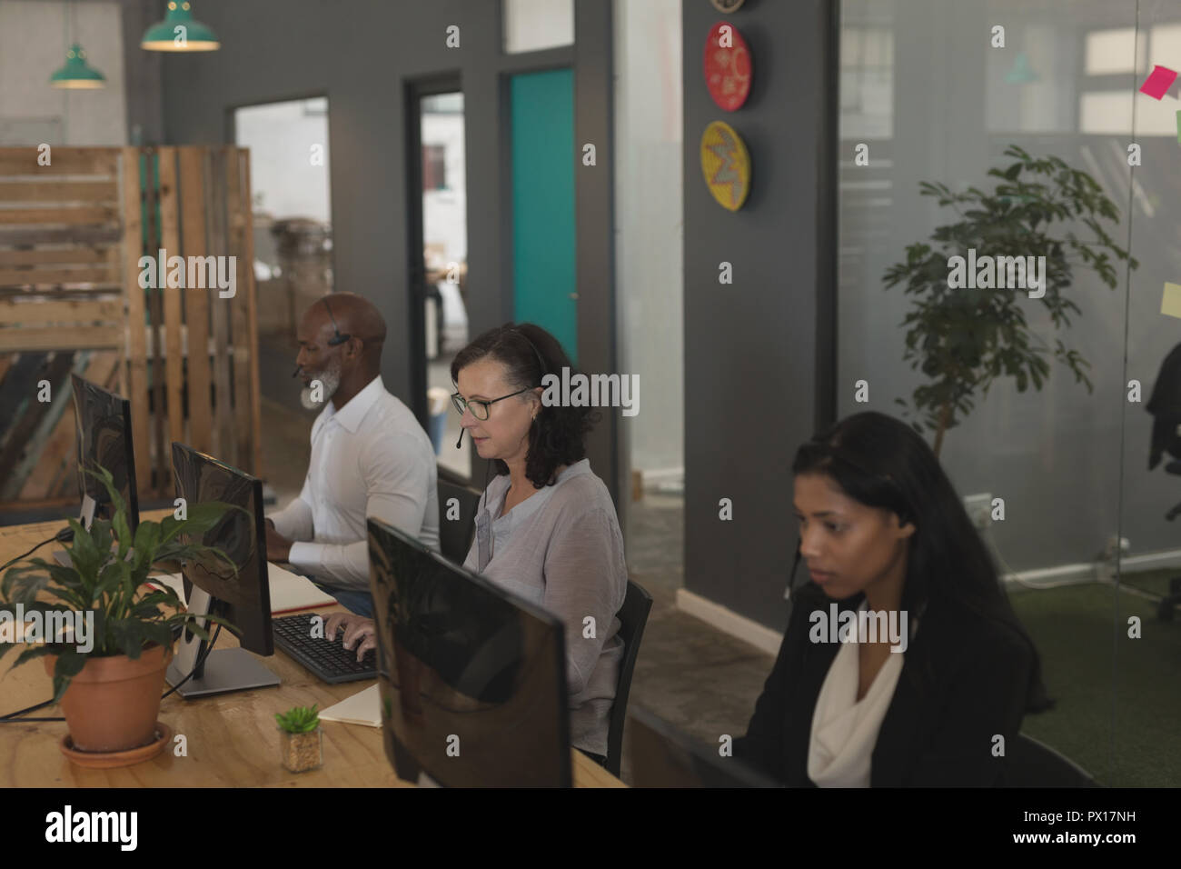 Executives working with headset on desk Stock Photo - Alamy