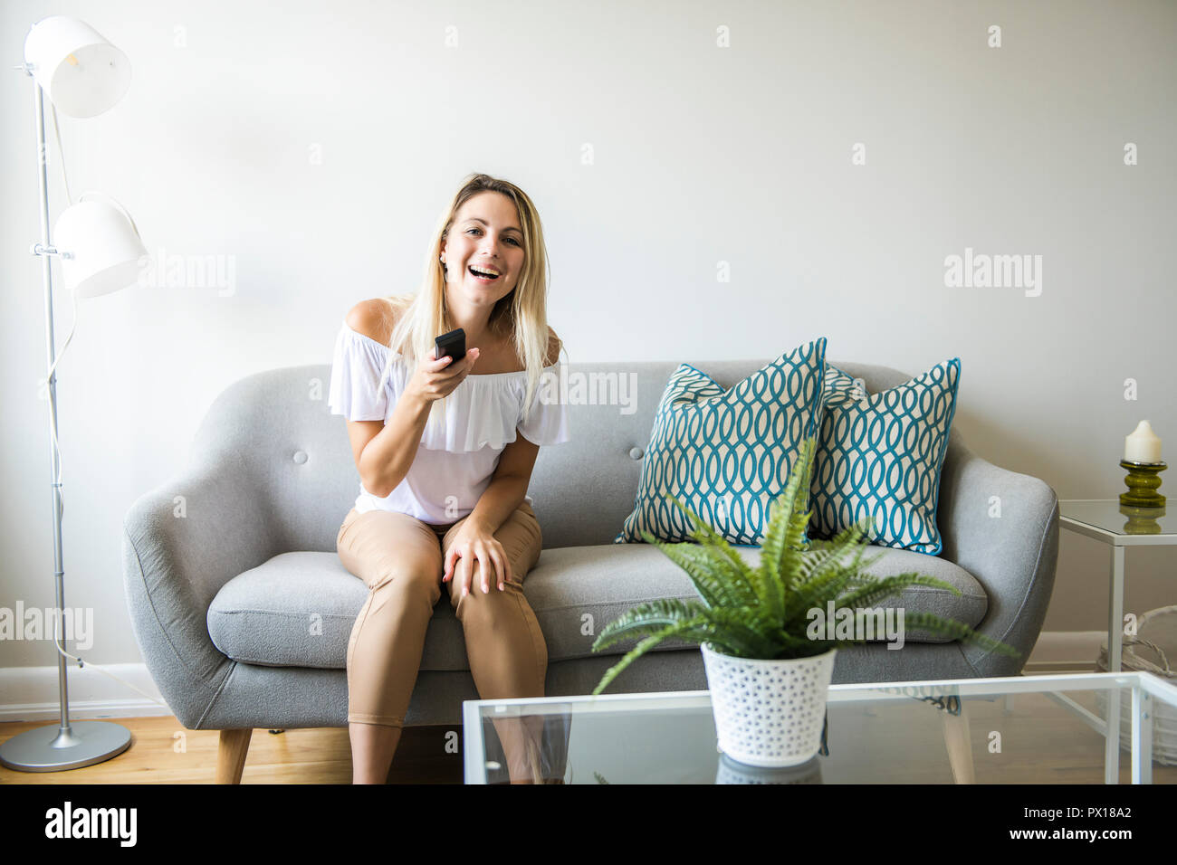 Women watching TV on the sofa at home with remote control Stock Photo ...