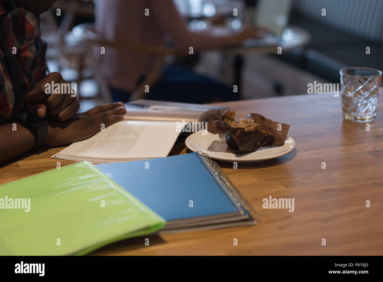 Plate of dessert and businessman reading a book in cafeteria Stock ...