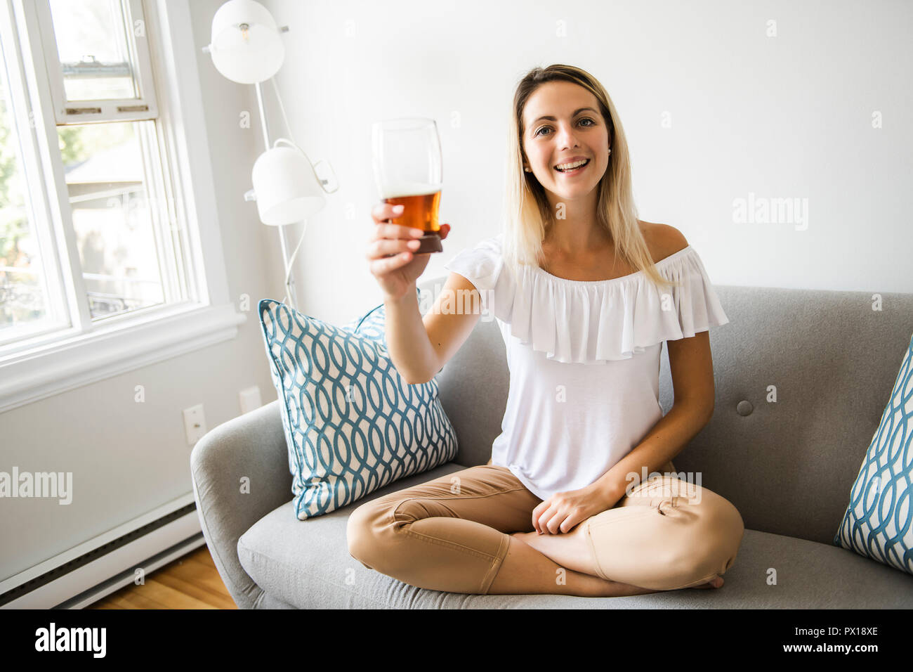 Woman drinking beer sitting on a couch in the living room at home Stock ...