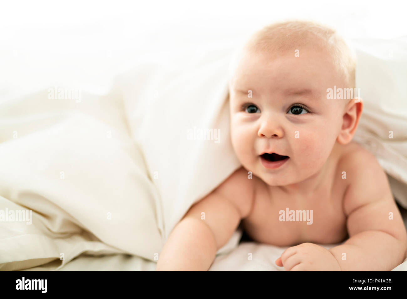 happy cute baby lying on white sheet Stock Photo - Alamy