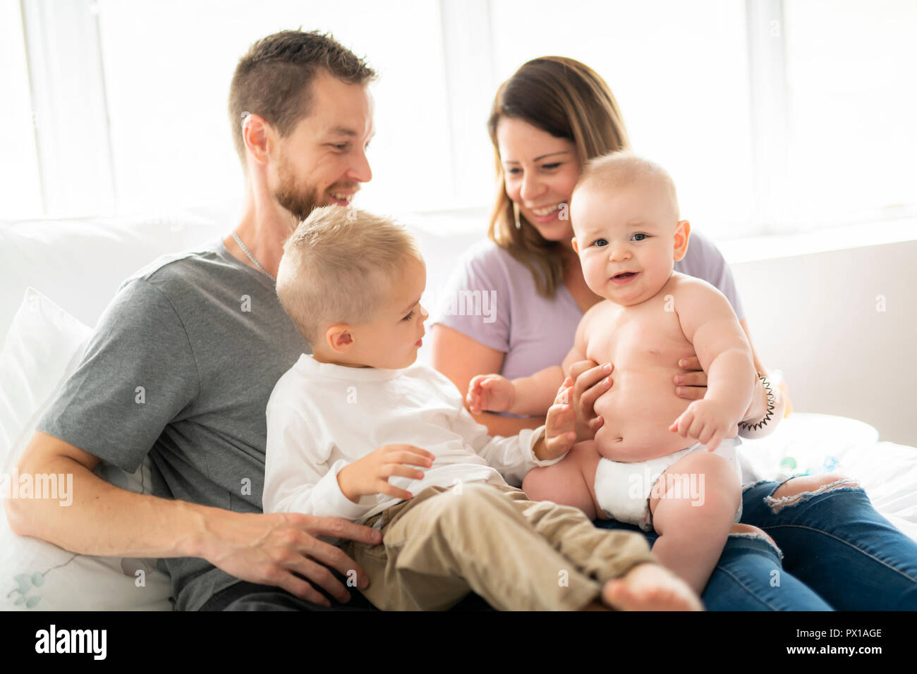 Family of four with baby having fun on bed Stock Photo - Alamy