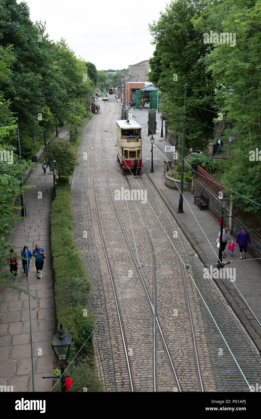 An old tram carrying passengers approaches te bridge at Crich Tramway ...