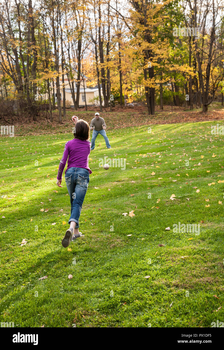 Preteen girl plays baseball catch in backyard with father, Northeast ...