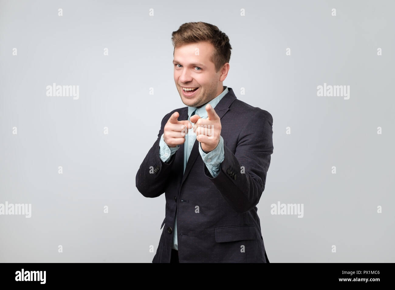 Studio portrait of handsome caucasian guy in suit expressing positive ...