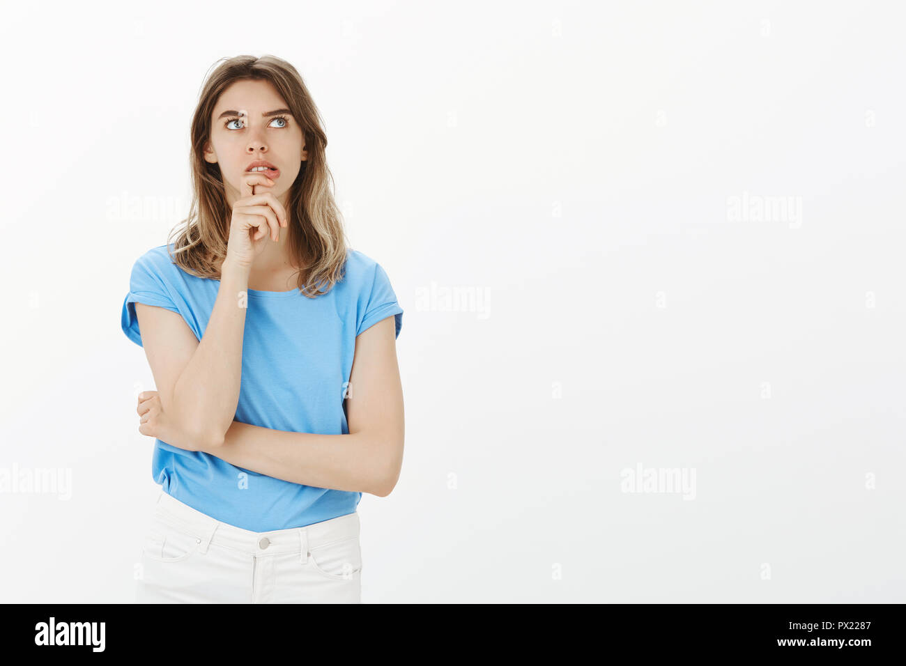 Indoor shot of focused seriuos cute woman with fair hair, looking up ...