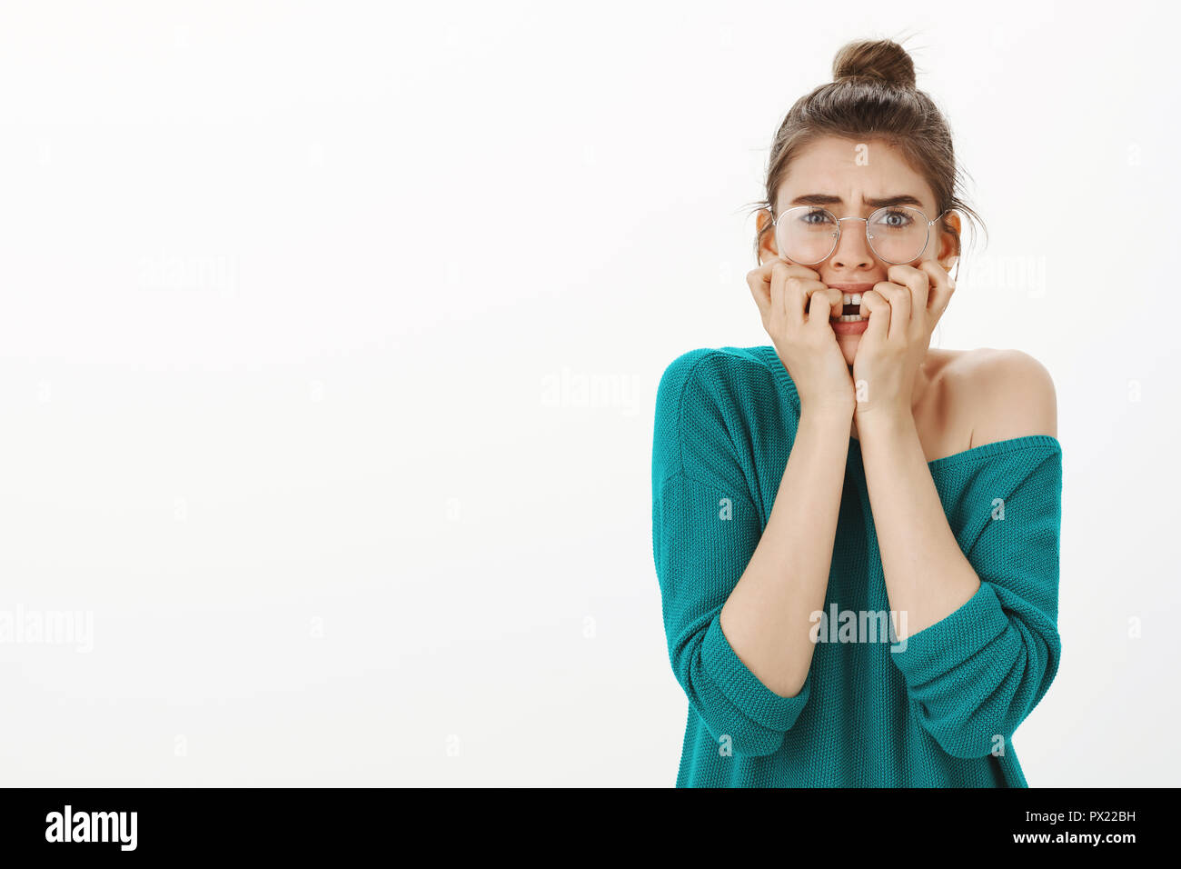 Studio shot of shocked and scared young woman in transparent glasses ...