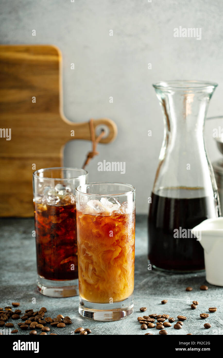 Refreshing cold brew iced coffee in tall glasses with milk or creamer ...