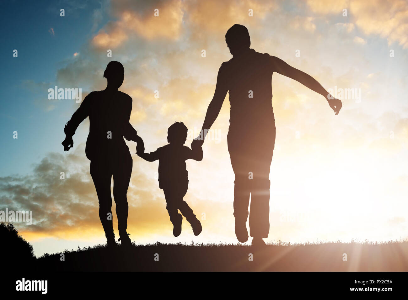 Silhouette Of Parents Having Fun With Their Child At Sunset Stock Photo ...