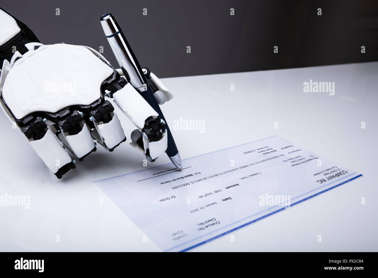 Robotic Hand Signing Cheque With Pen On Desk Stock Photo - Alamy