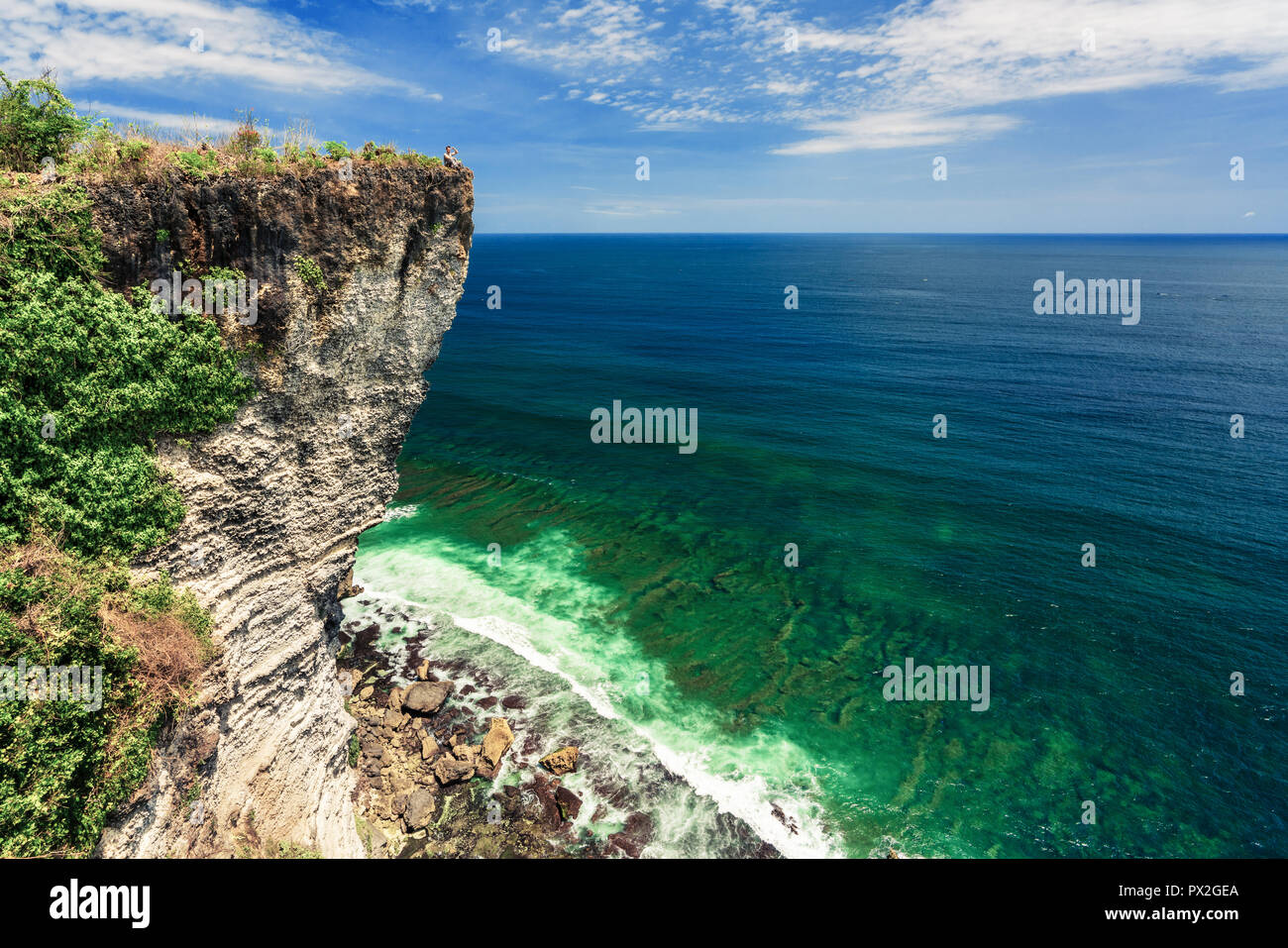 Man standing with raised hands on the cliff with amazing ocean and ...