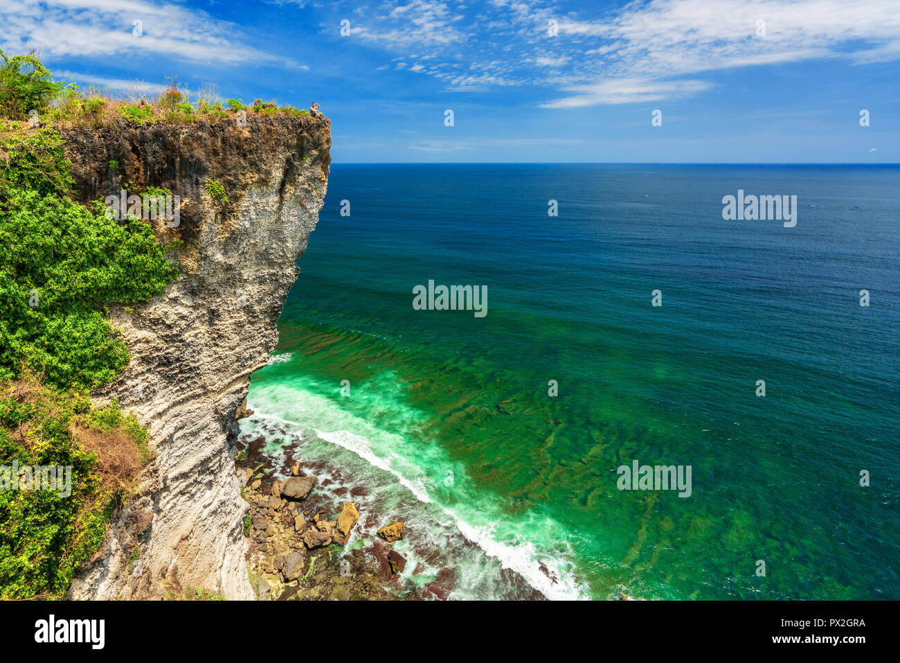 Man standing with raised hands on the cliff with amazing ocean and ...