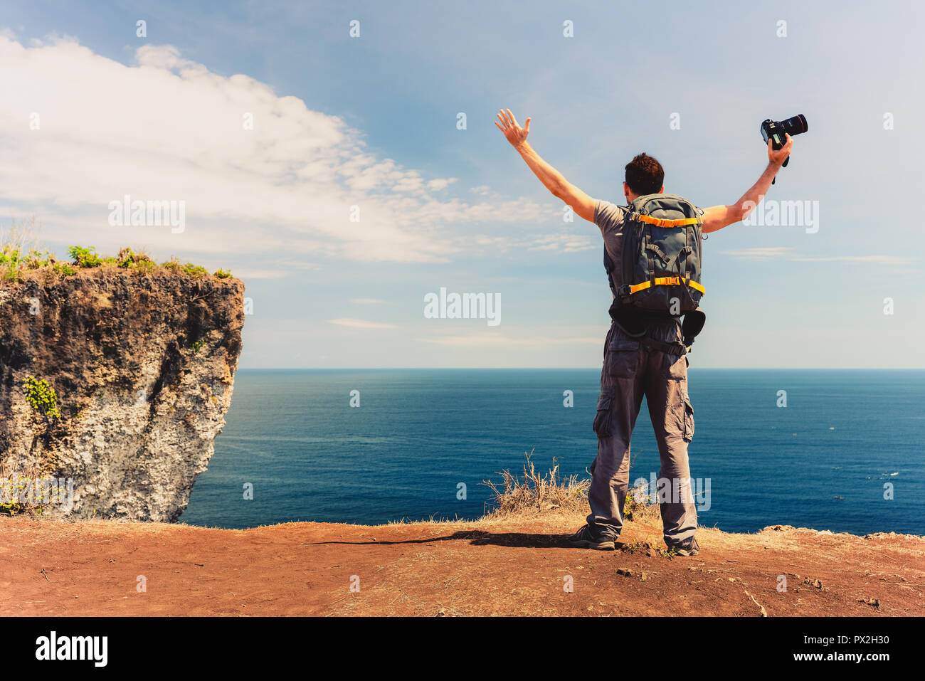 Escape to nature: happy travel man with camera in hand standing on top ...