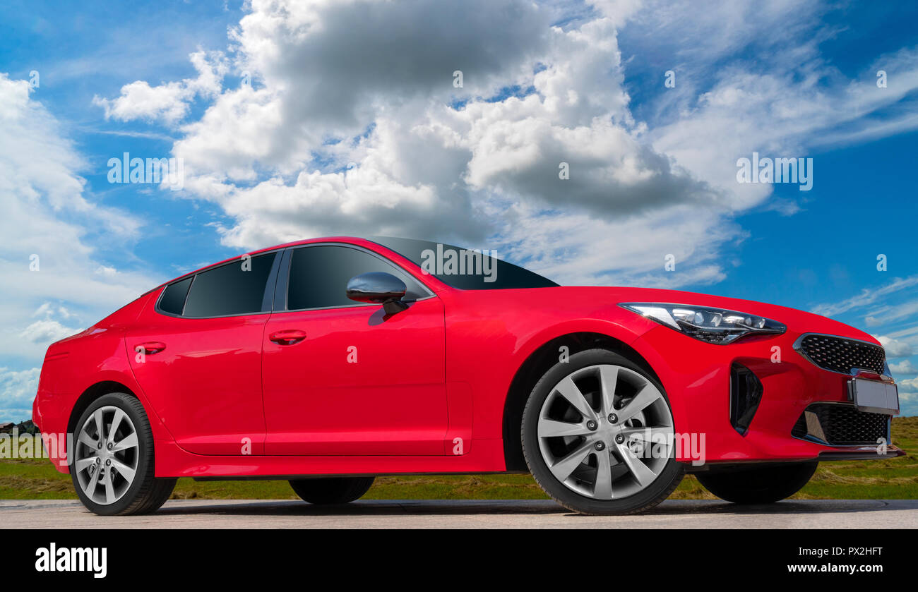 Red car on a blue sky background with white clouds. A stylish, modern ...