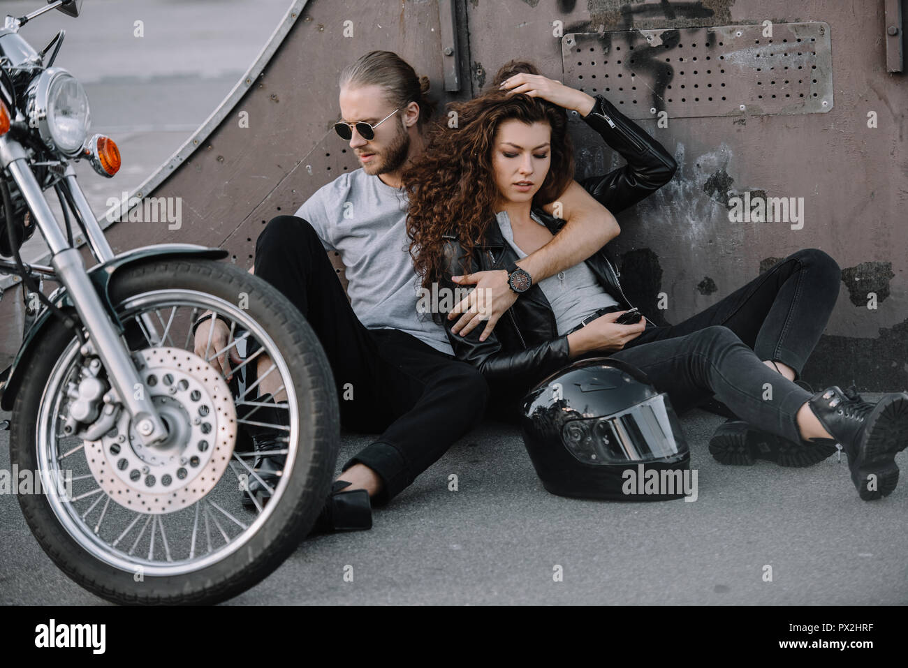 couple of bikers hugging and sitting on asphalt with helmet and ...