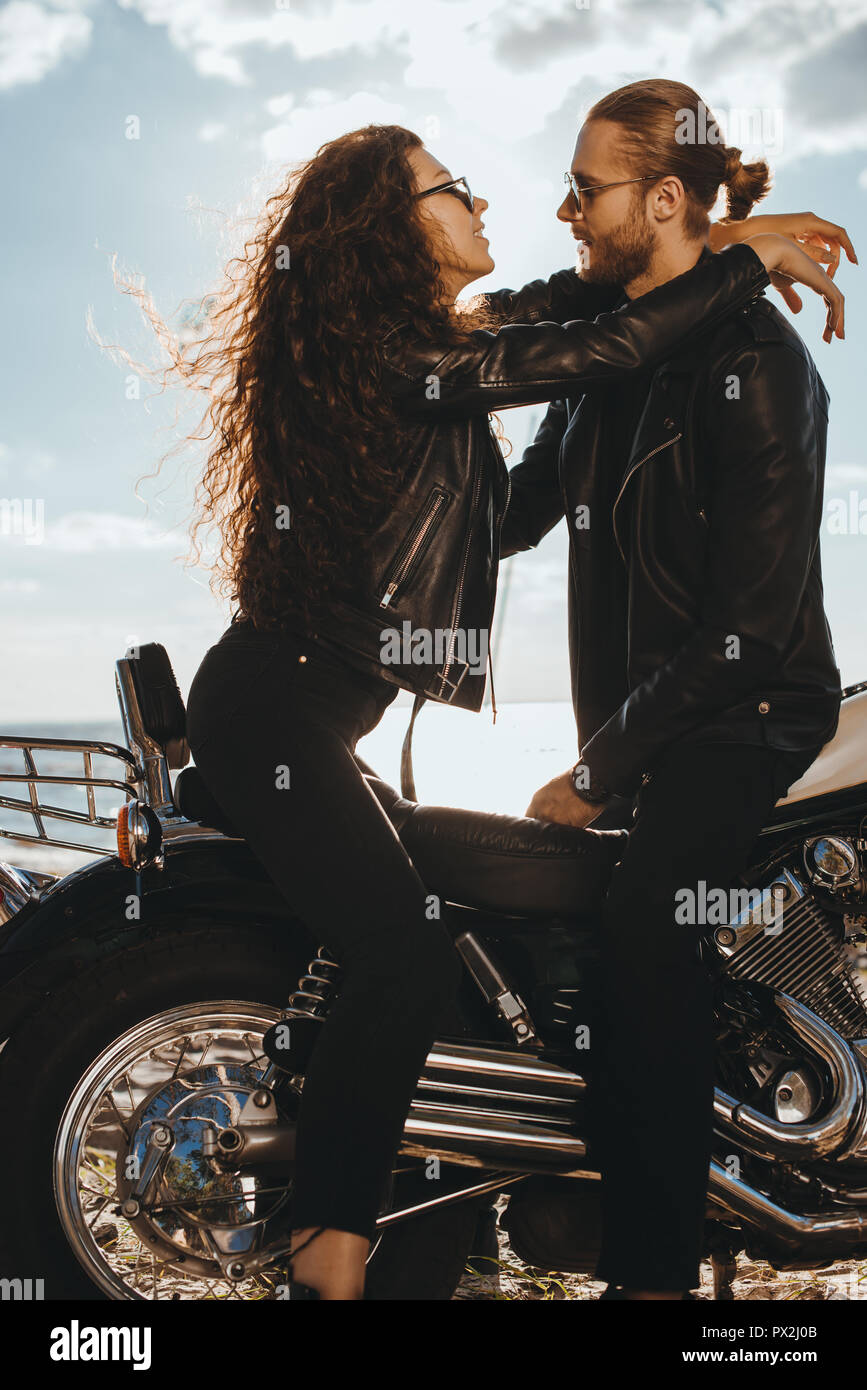 couple of bikers in black leather jackets hugging on chopper motorcycle ...