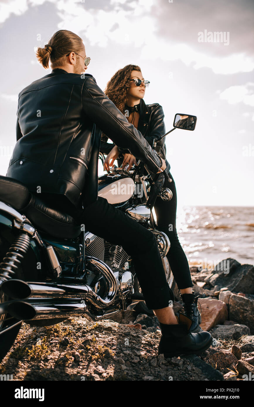 couple of bikers in black leather jackets with chopper motorcycle near ...