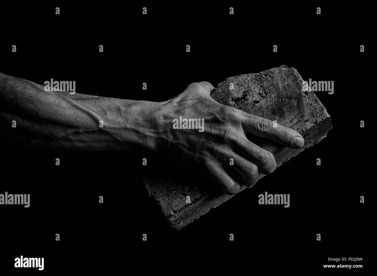Man's hand holding a brick, in black and white Stock Photo - Alamy