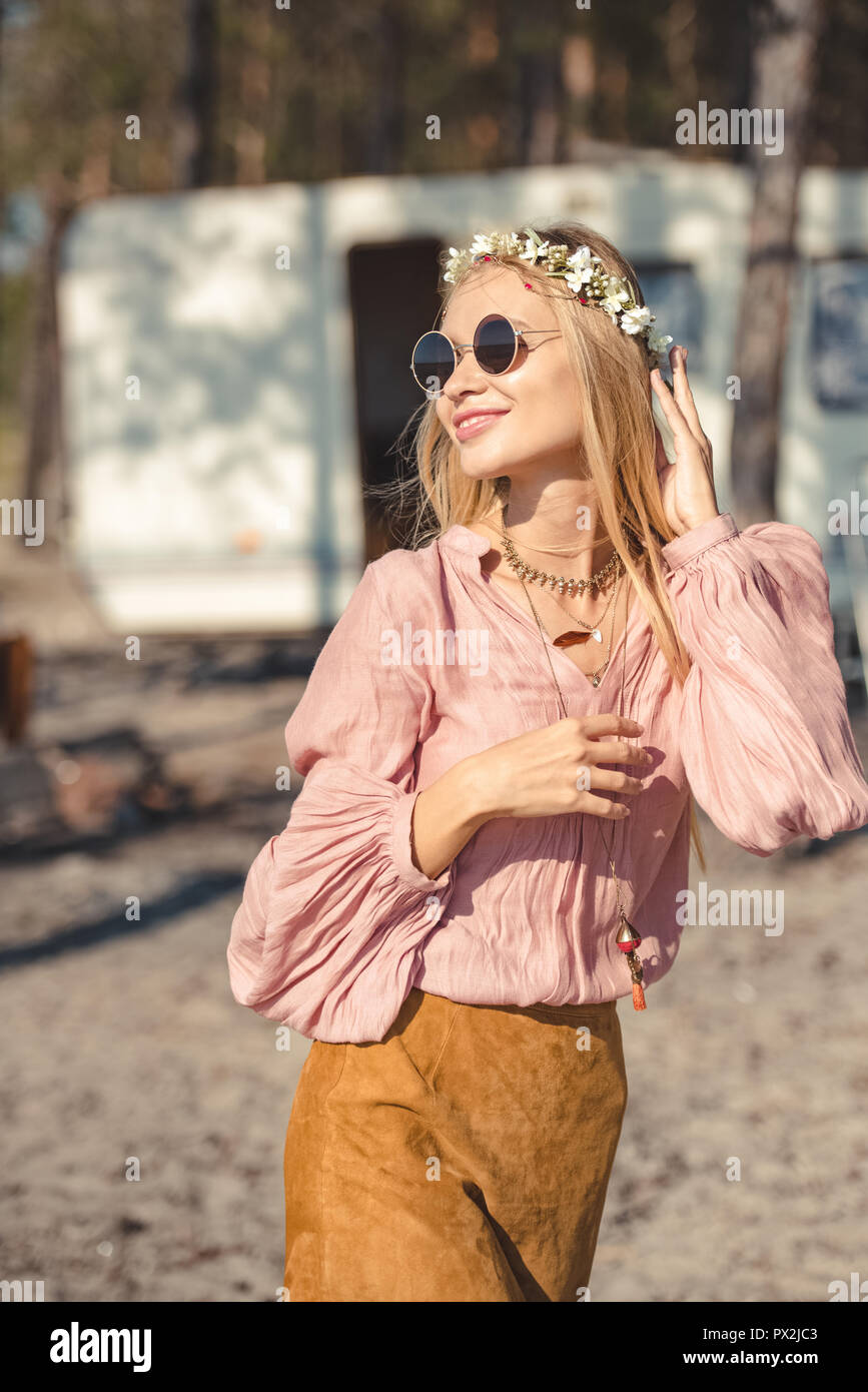 beautiful smiling hippie girl in wreath and sunglasses posing near ...