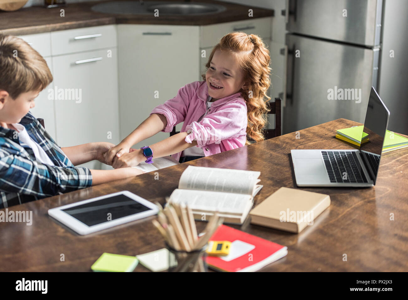 little brother and sister fighting for book while doing homework Stock ...
