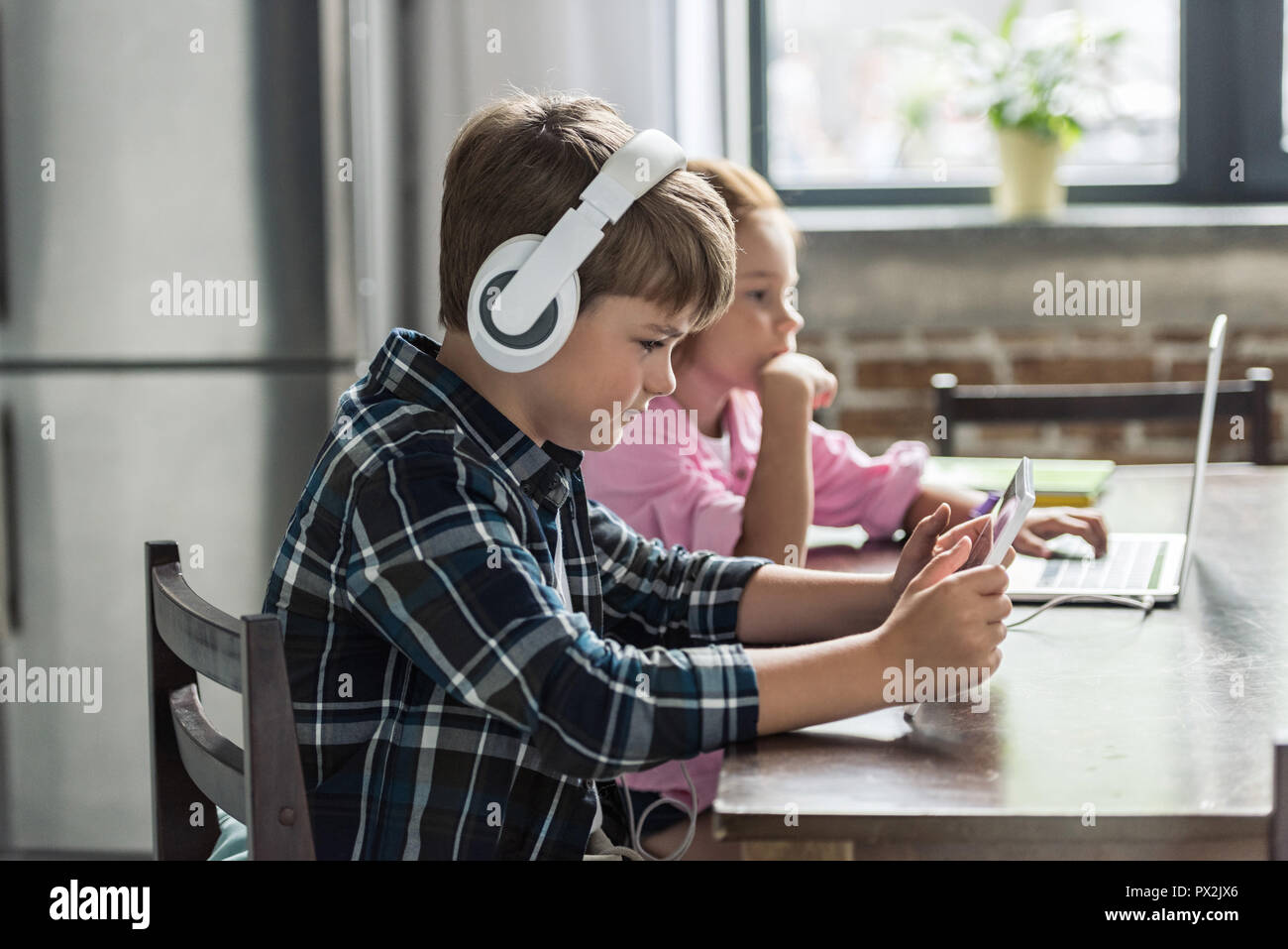 little brother and sister using digital devices at home Stock Photo - Alamy