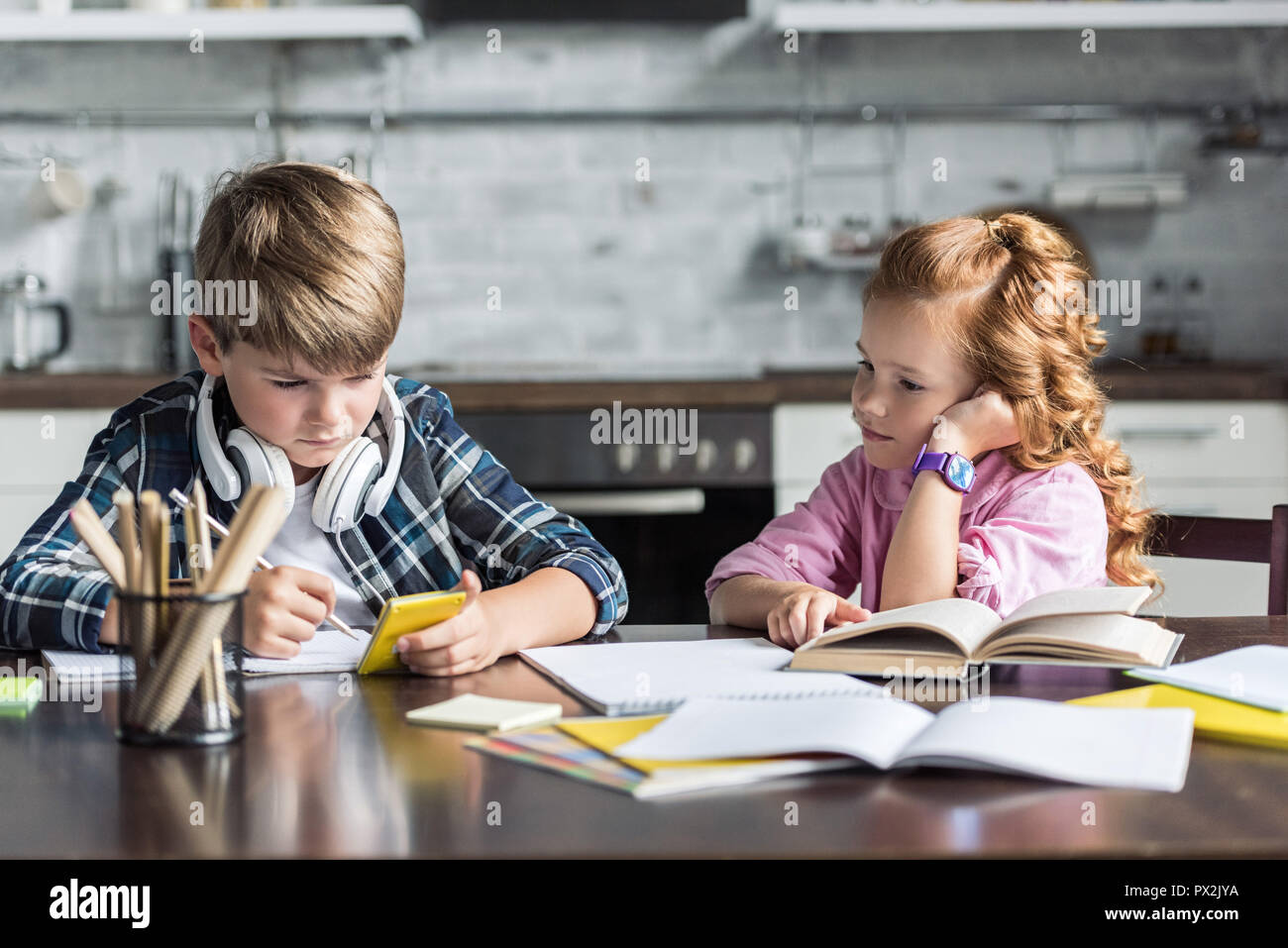 concentrated little kids doing homework together at kitchen Stock Photo ...