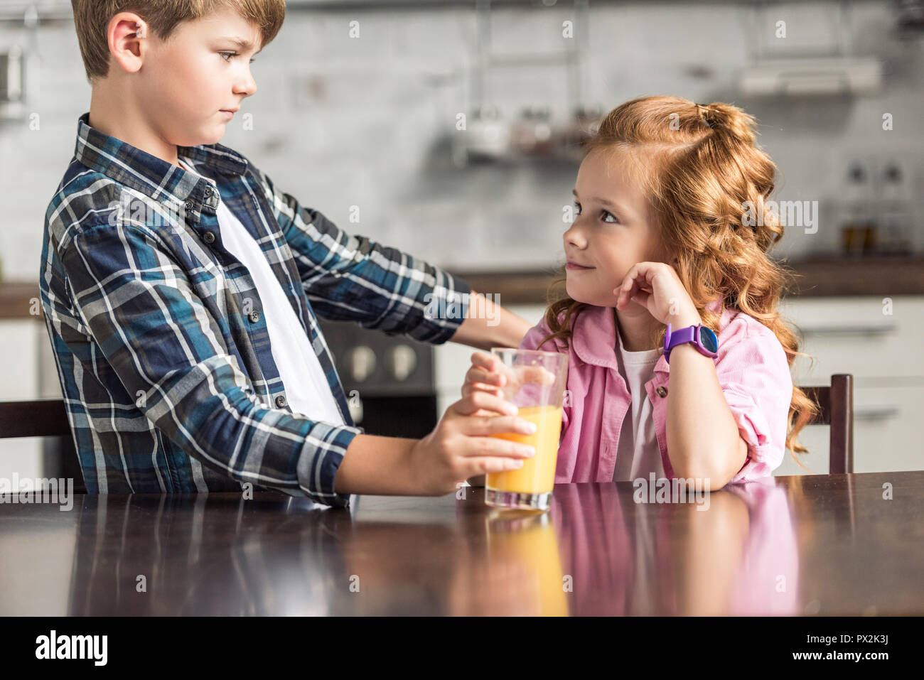 little brother giving glass of orange juice to his sister Stock Photo ...