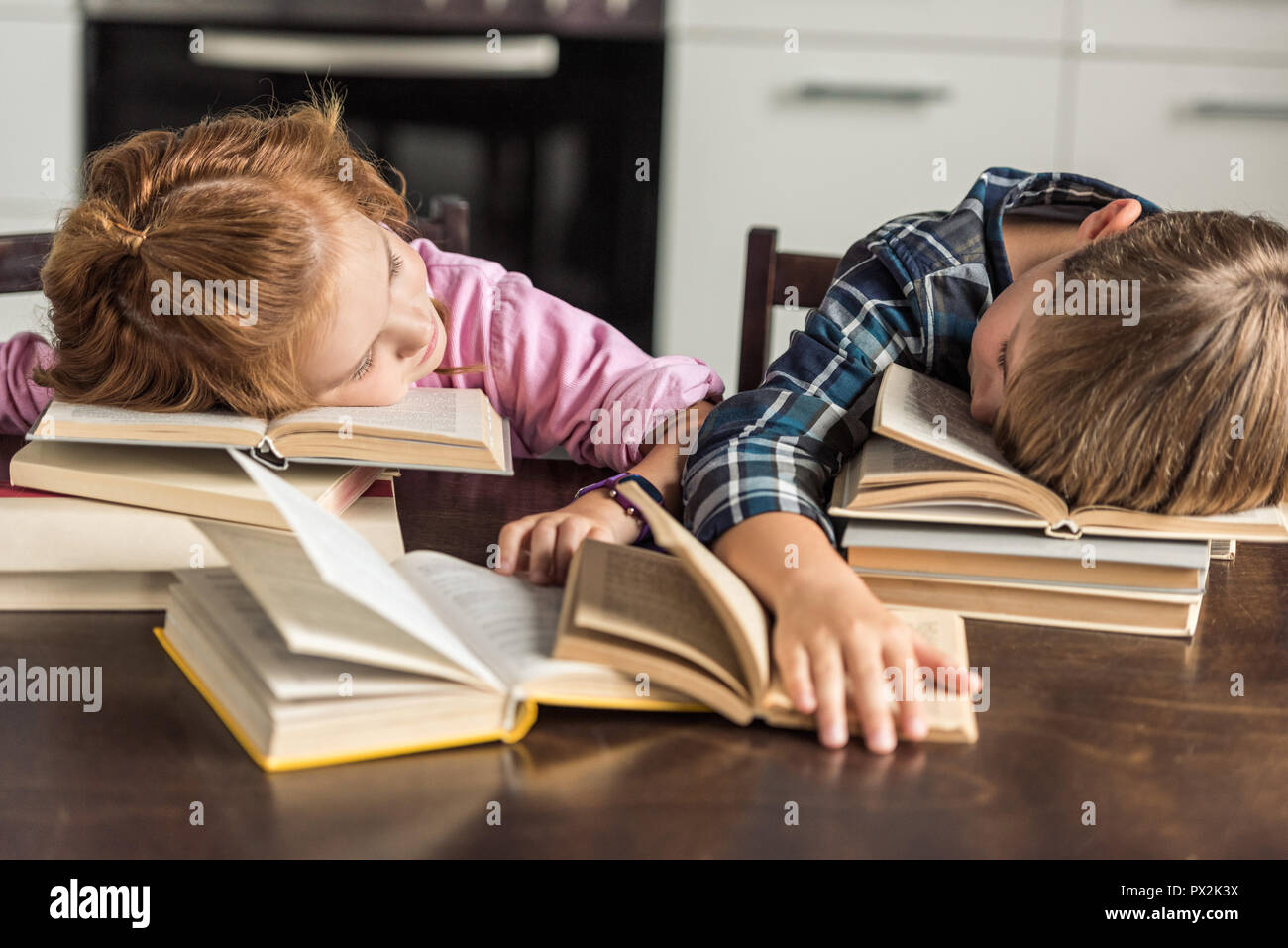exhausted little scholars sleeping on book while doing homework Stock ...