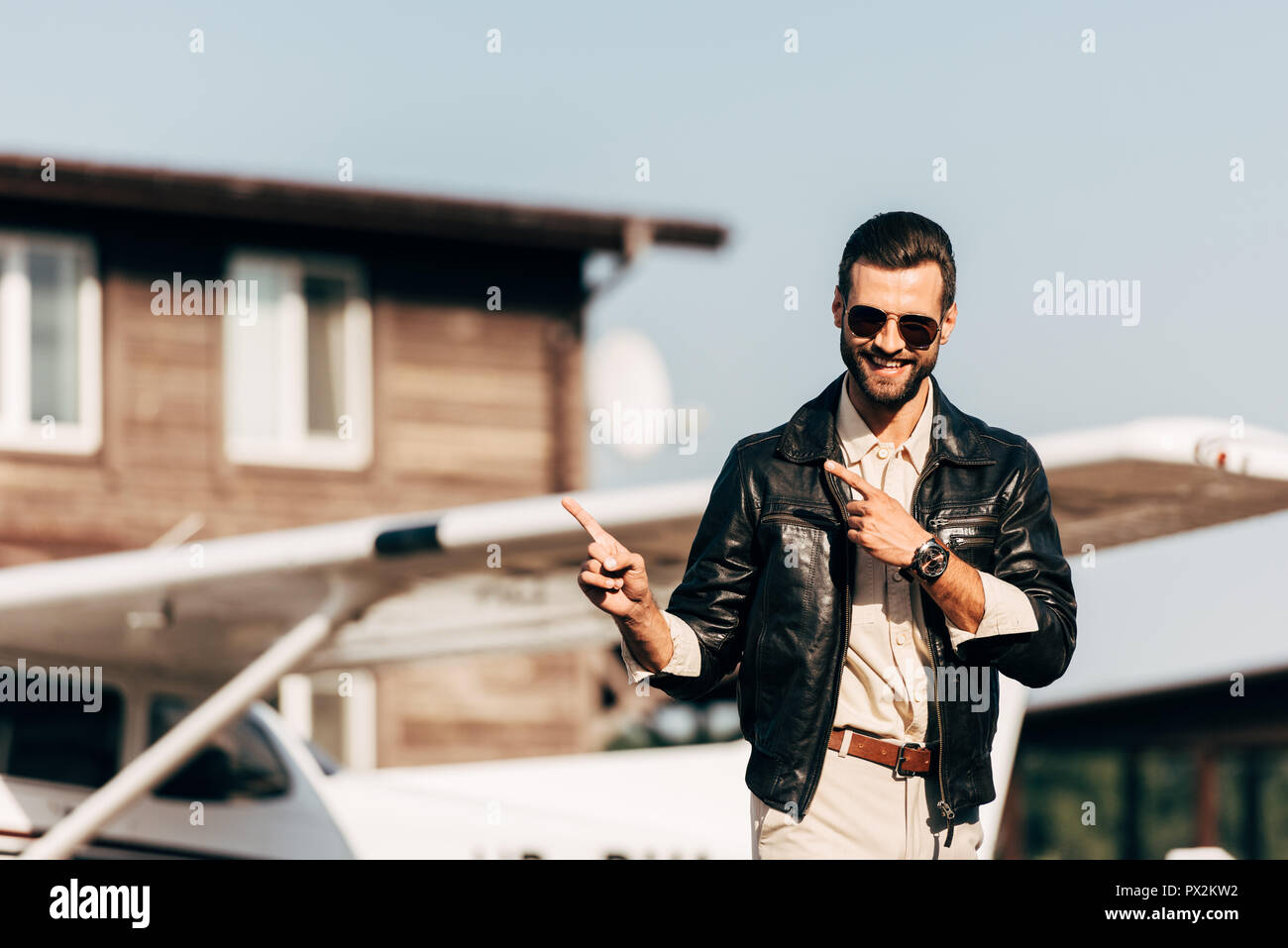 happy stylish man in leather jacket and sunglasses pointing by fingers ...