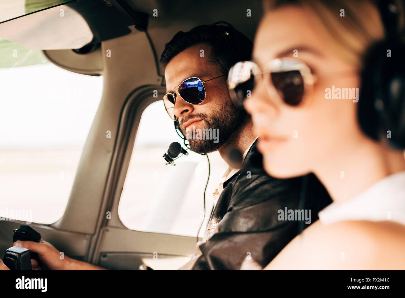 selective focus of handsome male pilot in headset and sunglasses ...