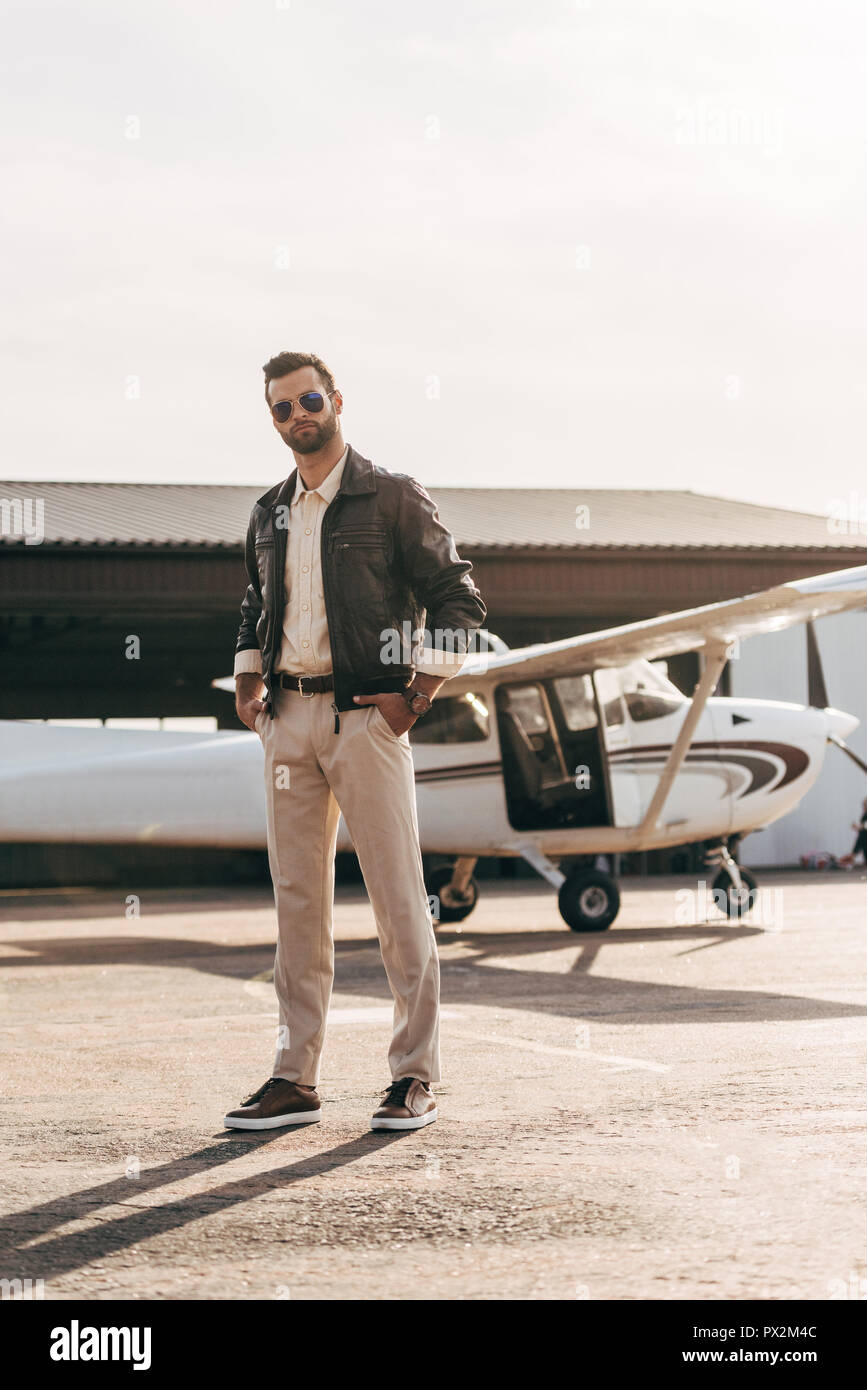 serious male pilot in leather jacket and sunglasses posing near ...