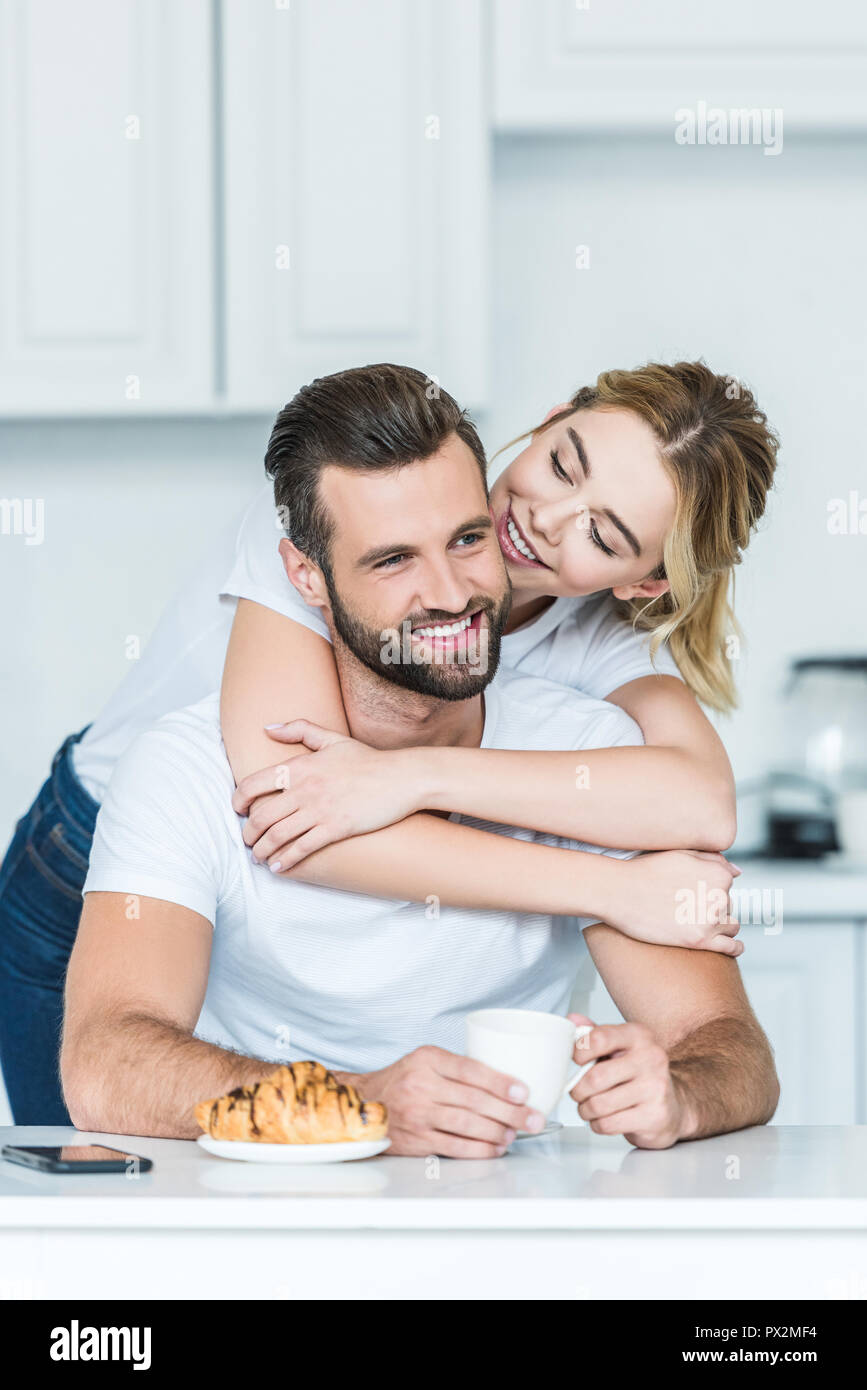 beautiful smiling young woman hugging happy boyfriend during breakfast ...