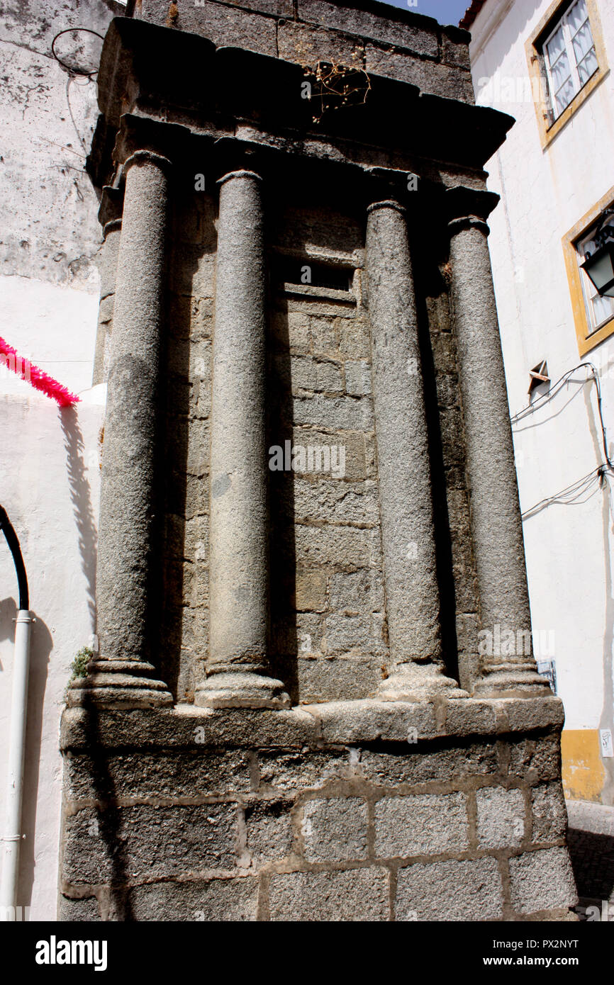 Old temple columns in a wall on Rua Nova in Evora, Portugal Stock Photo ...