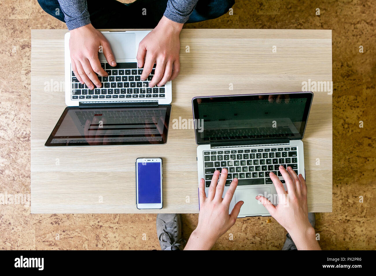 Two young people working on laptops in the office, writing a program ...