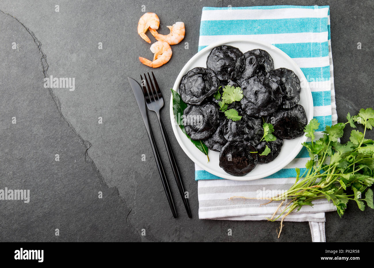 Traditional Italian black ravioli with srimps on white plate, gray ...