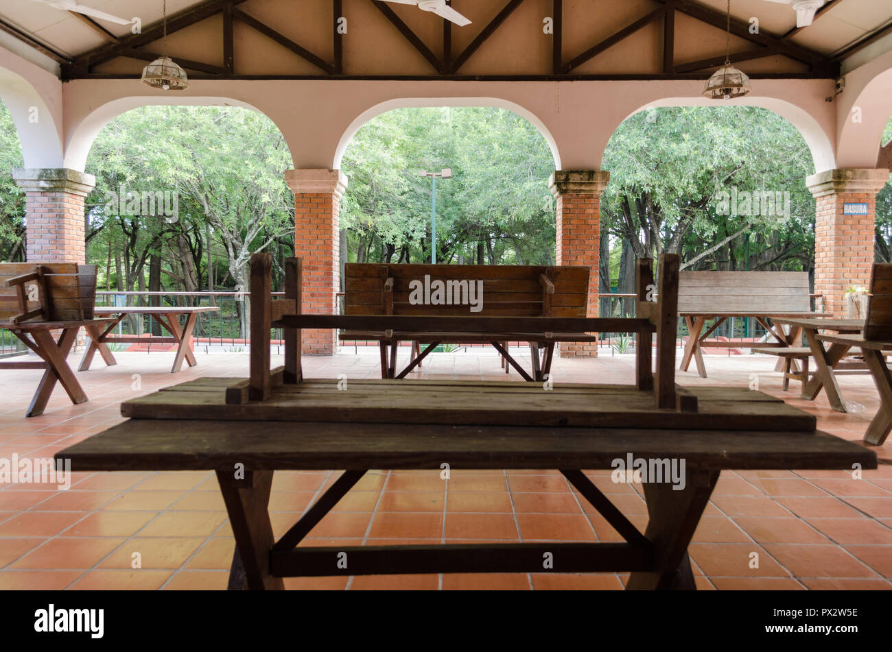 inside the roof of a wooden hut, with brown wooden tables and benches ...