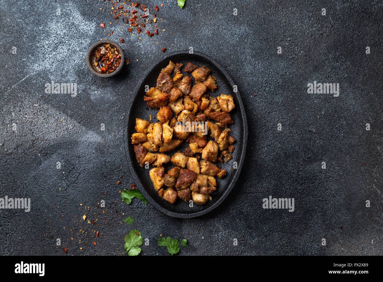 COLOMBIAN CHICHARRON. Fried pork chicharron on black plate. Top view ...