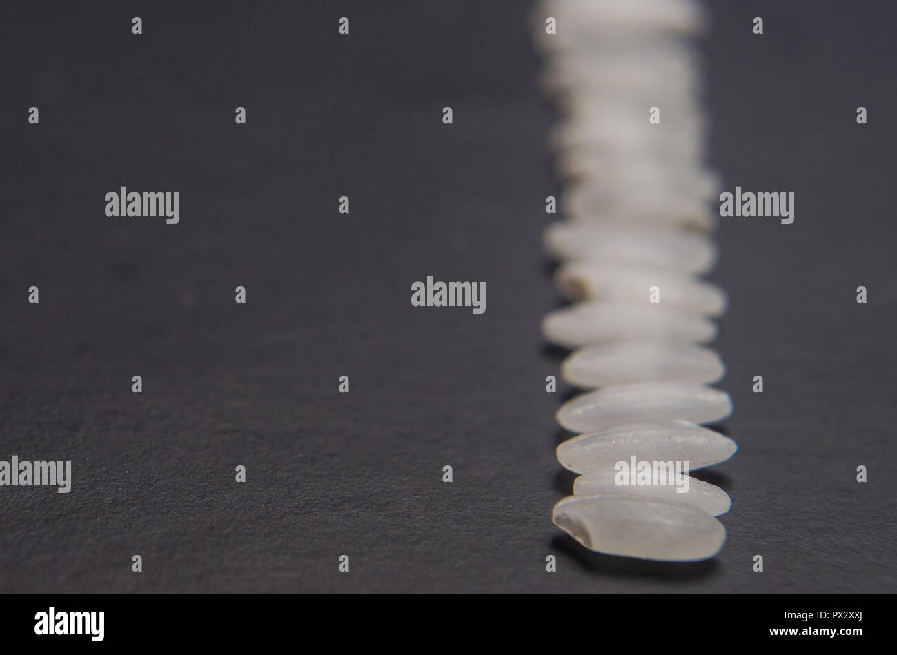 White rice scattered on a black background isolated in the shape of a ...