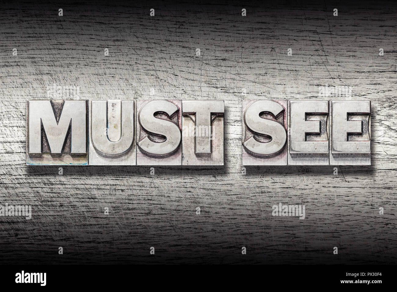 must see phrase made from metallic letterpress on rough wooden texture ...