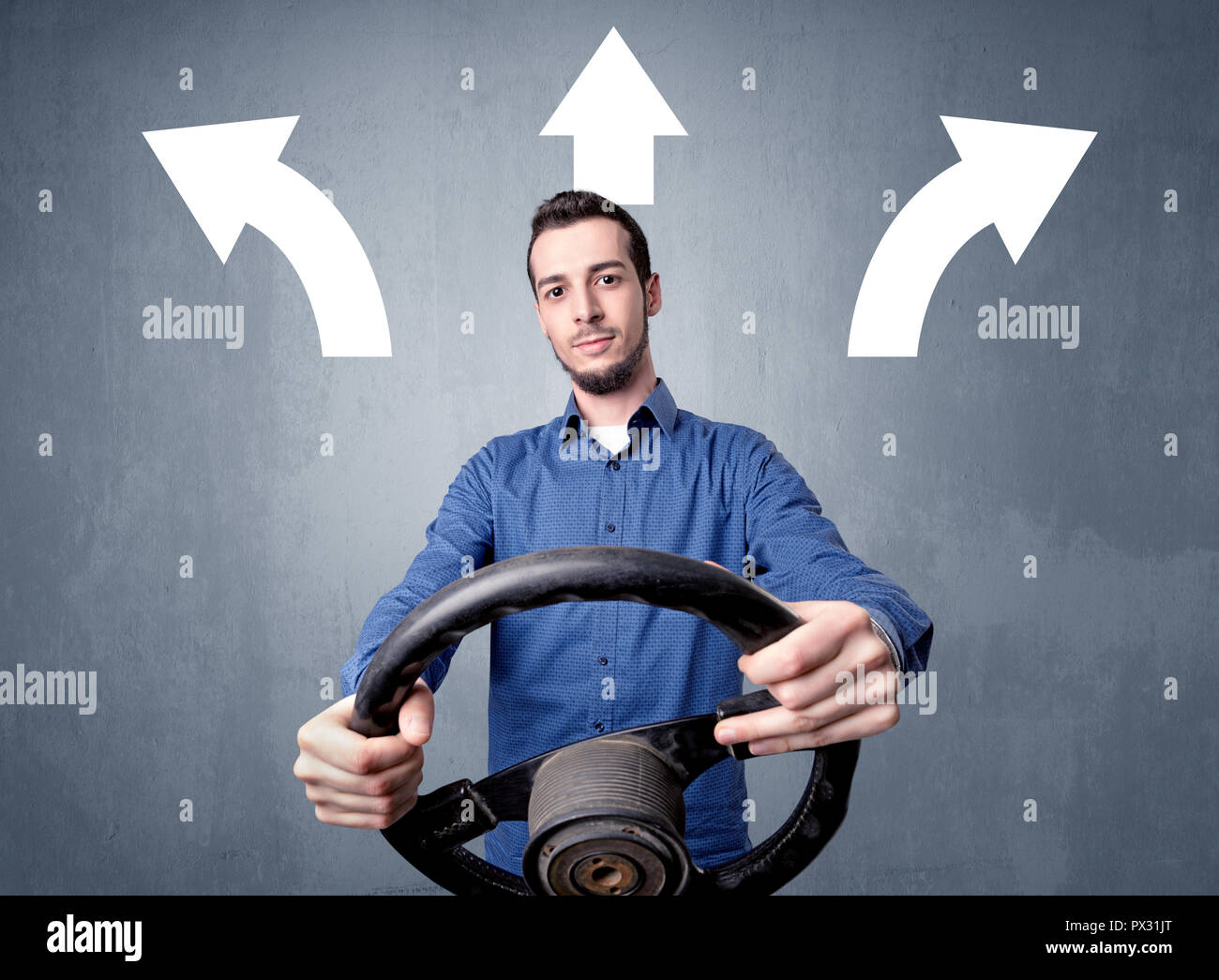 Young man holding black steering wheel with three arrows above his head ...