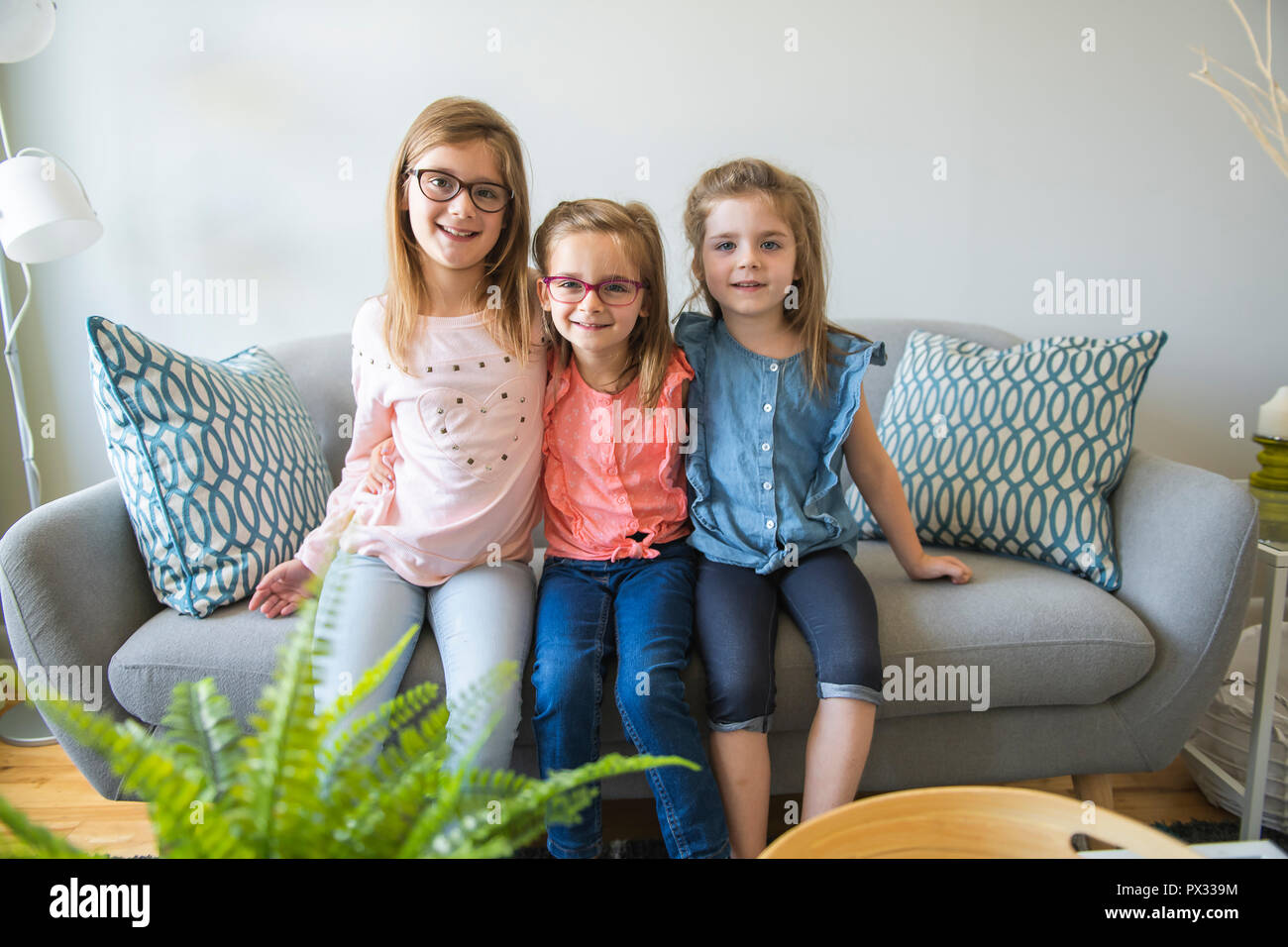 Three sisters girls sit on the sofa at home Stock Photo - Alamy
