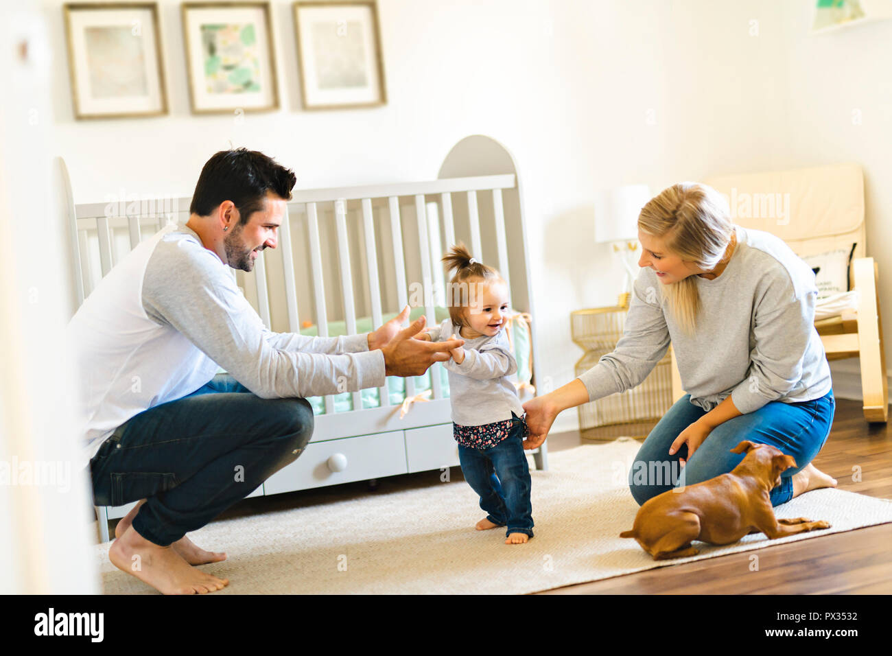 little baby girl first steps with the help of parent Stock Photo - Alamy