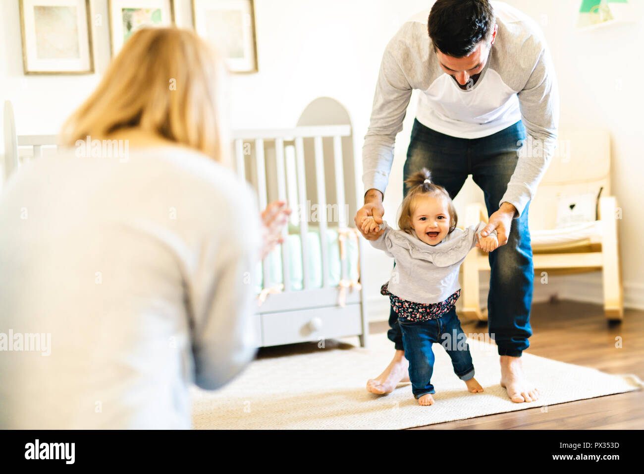 little baby girl first steps with the help of parent Stock Photo - Alamy