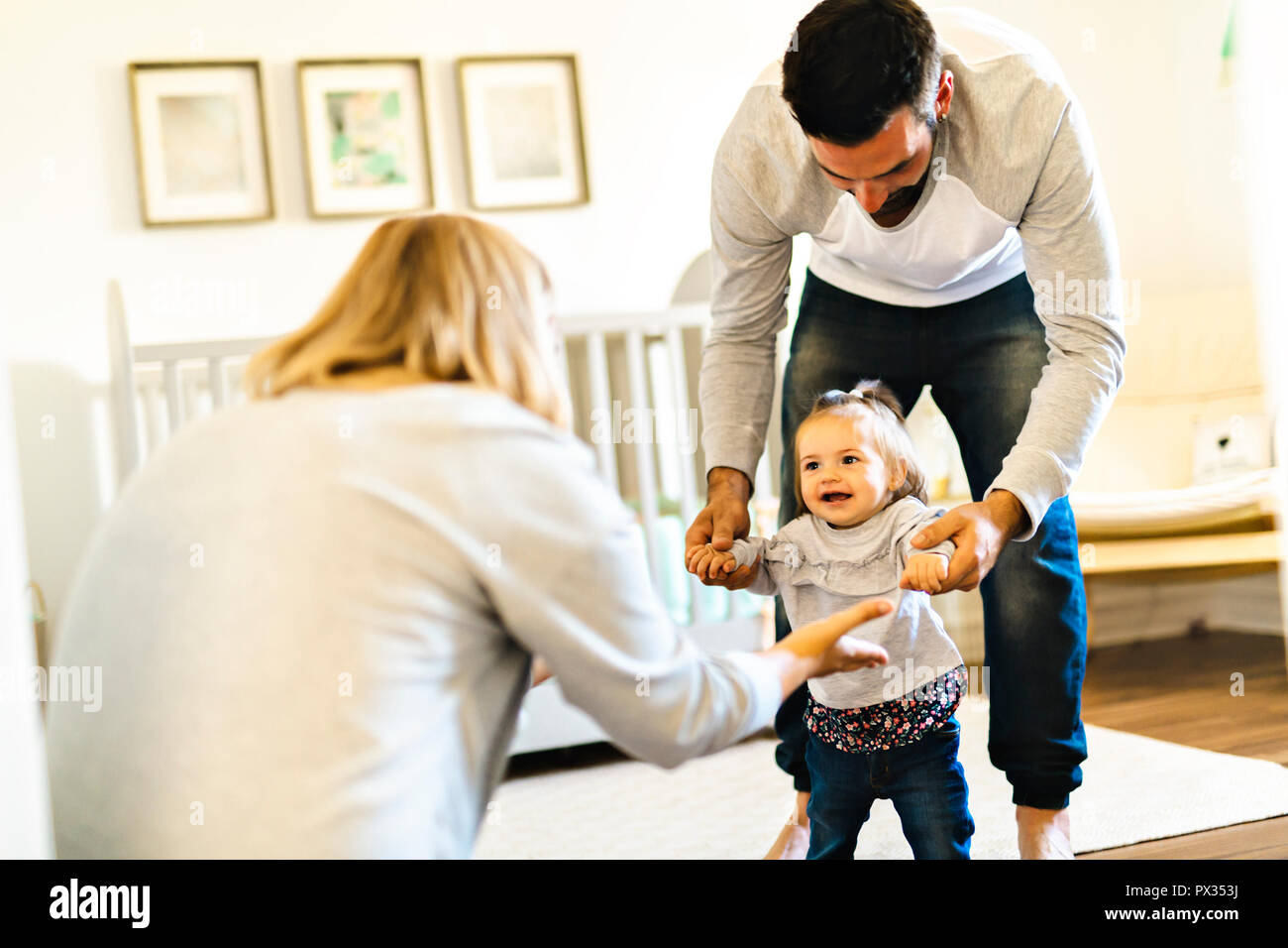 little baby girl first steps with the help of parent Stock Photo - Alamy