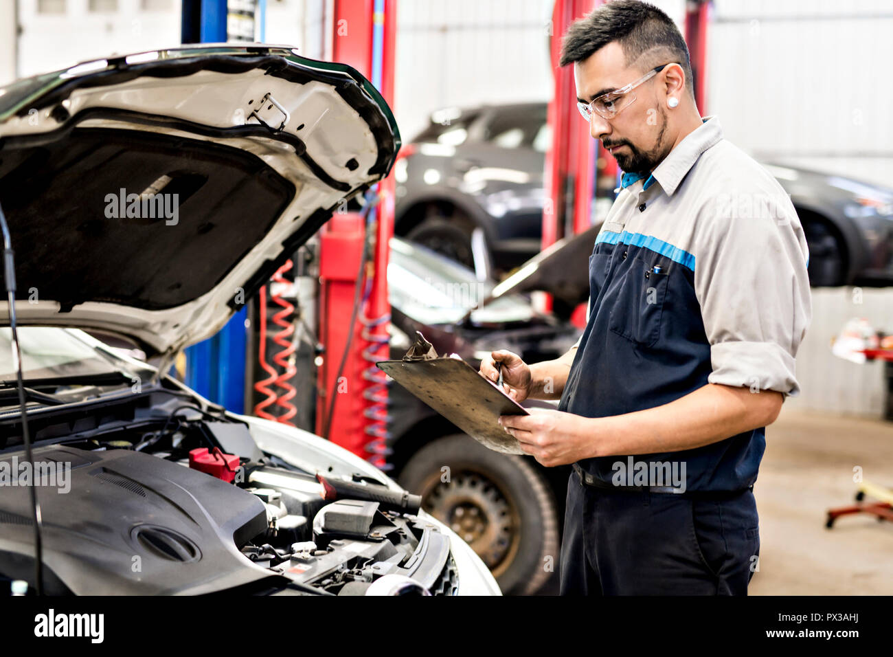 Handsome mechanic job in uniform working on car Stock Photo - Alamy