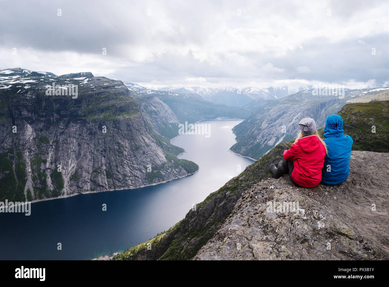Trolltunga - most spectacular Norway sights. Couple of travelers sits ...