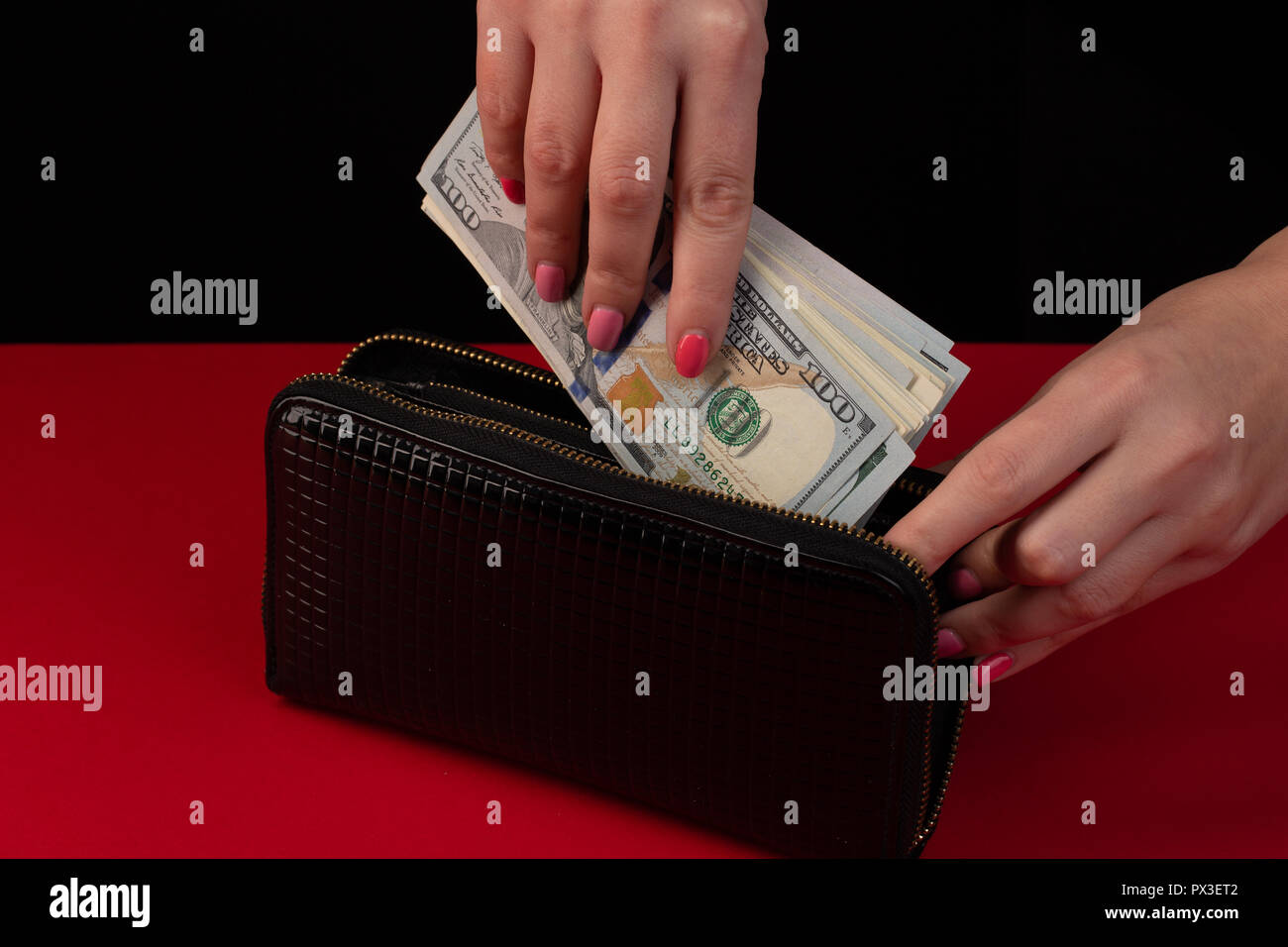 In the women's hands is the black leather wallet with a wad of hundred ...